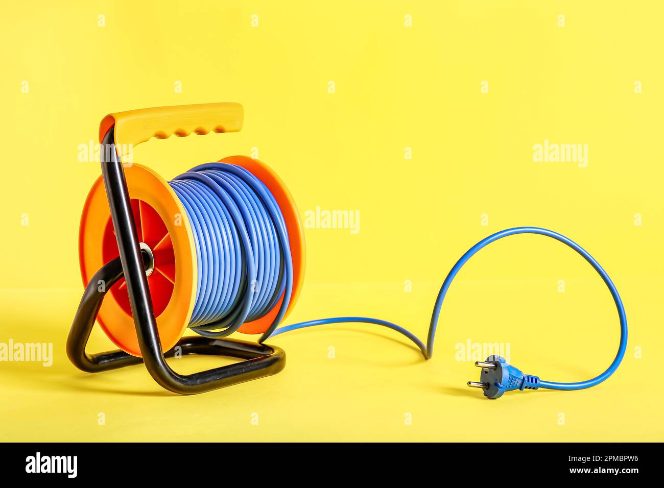 Extension electric cable reel on yellow background Stock Photo - Alamy