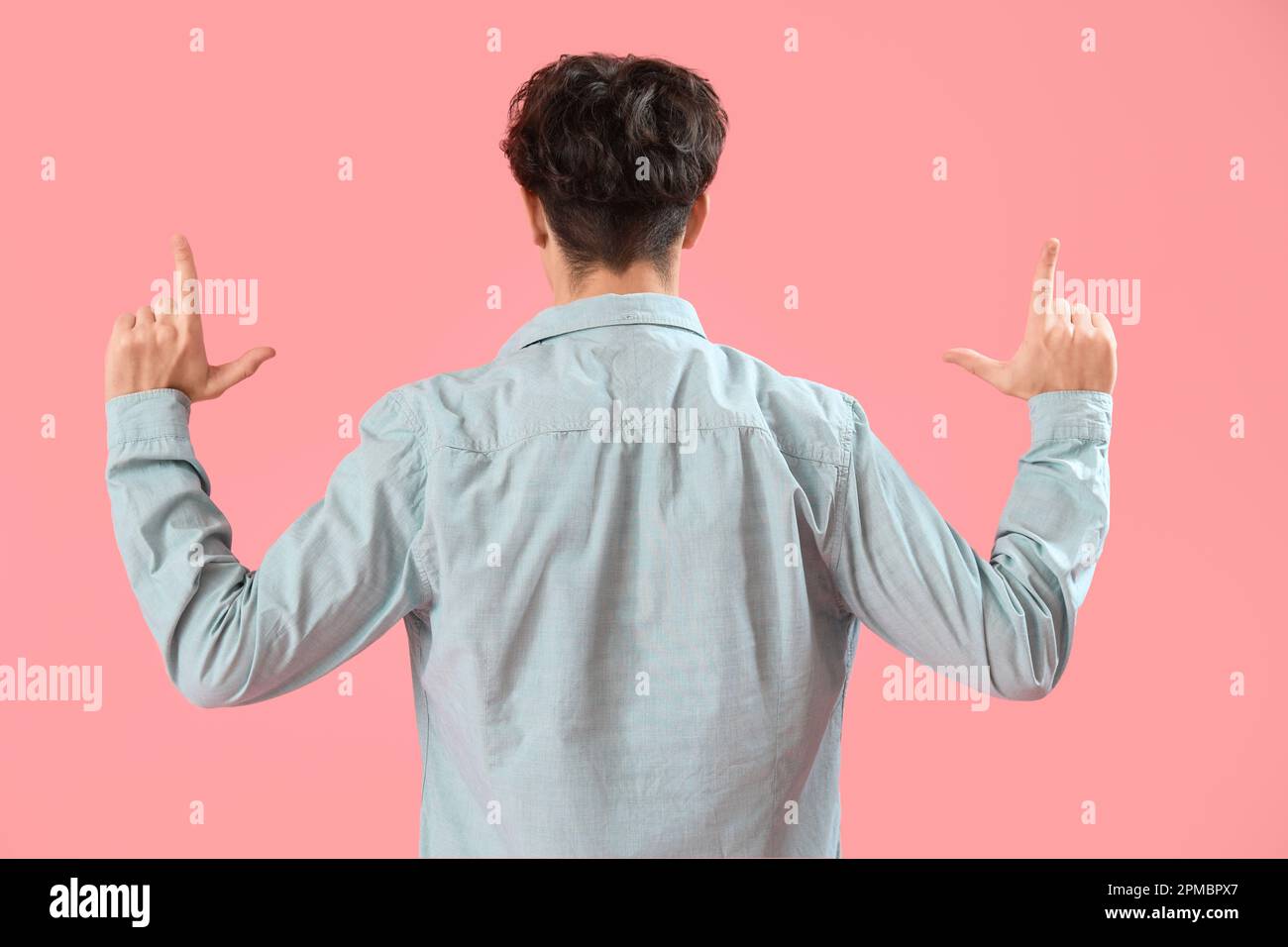 Young man showing loser gesture on pink background, back view Stock ...