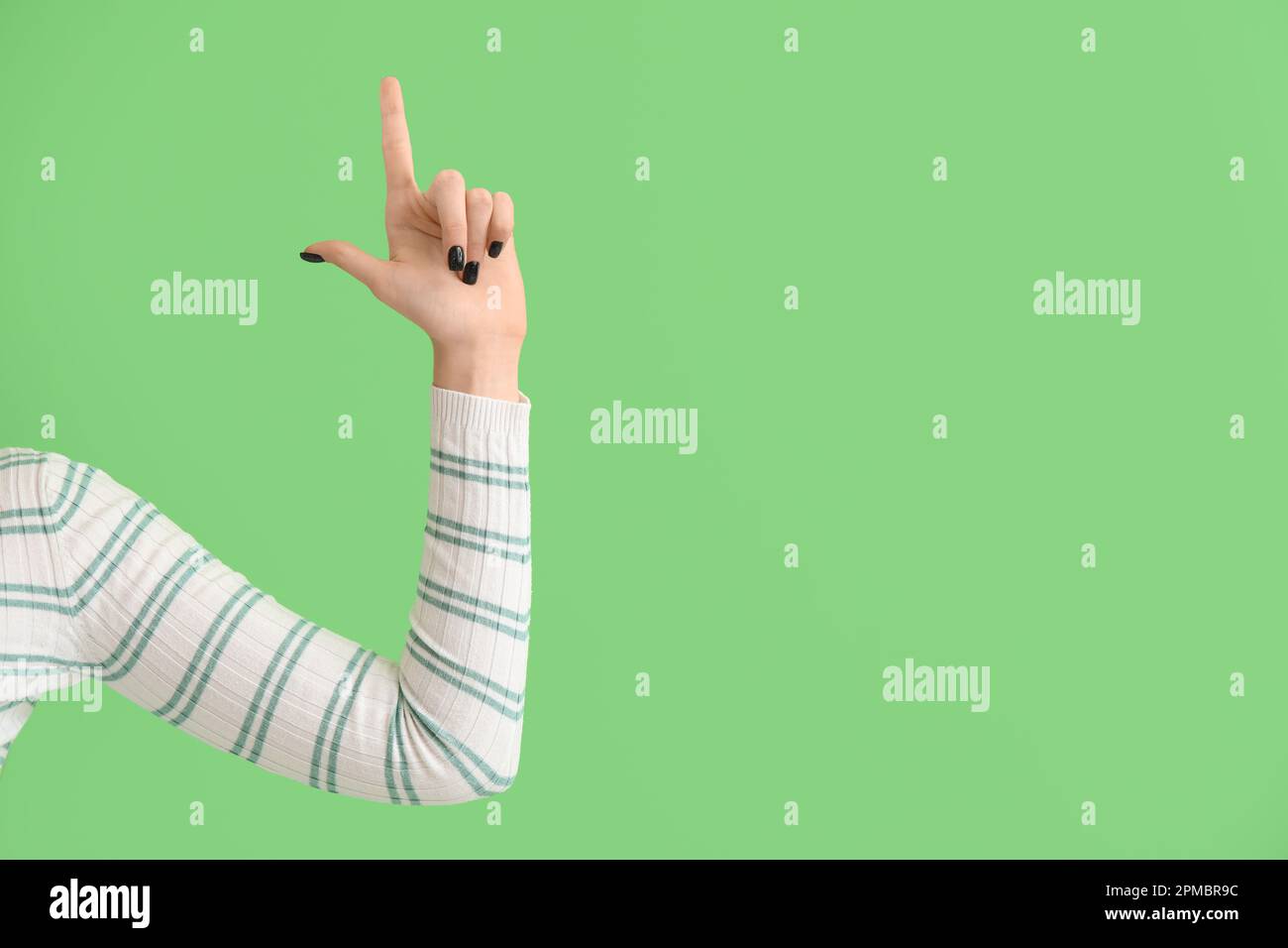 Hand of woman showing loser gesture on green background Stock Photo - Alamy