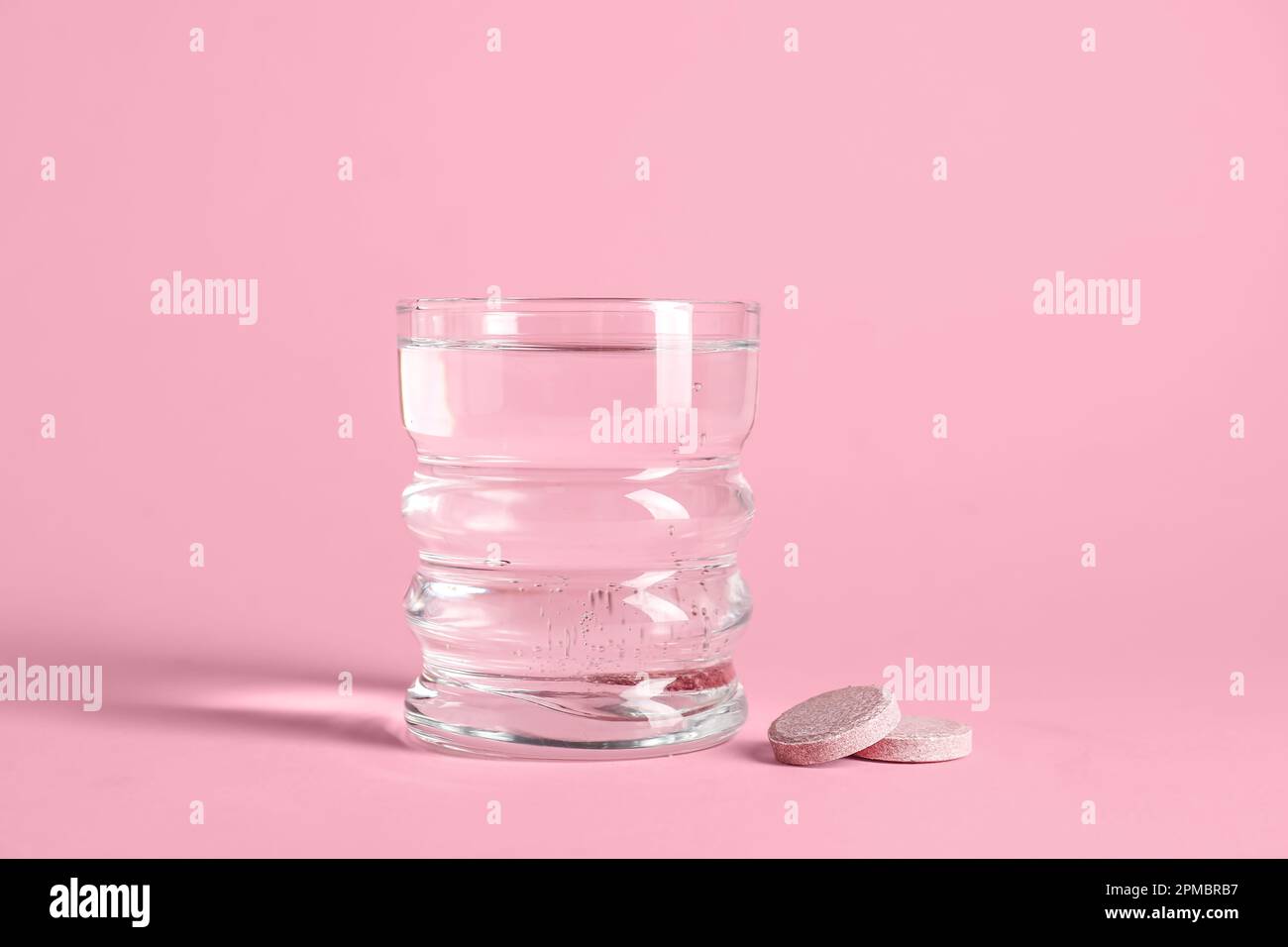 Glass of water with soluble tablets on pink background Stock Photo - Alamy