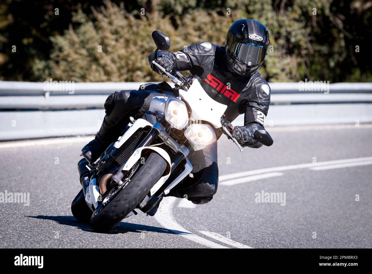 Rider on the asphalt with his bike leaning around a curve Stock Photo ...