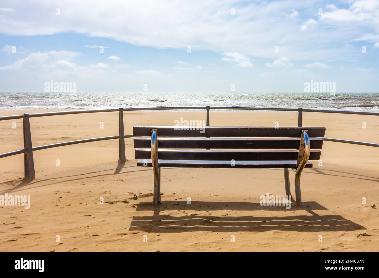 A bench, protected by a semi circle of metal railings looking out to ...