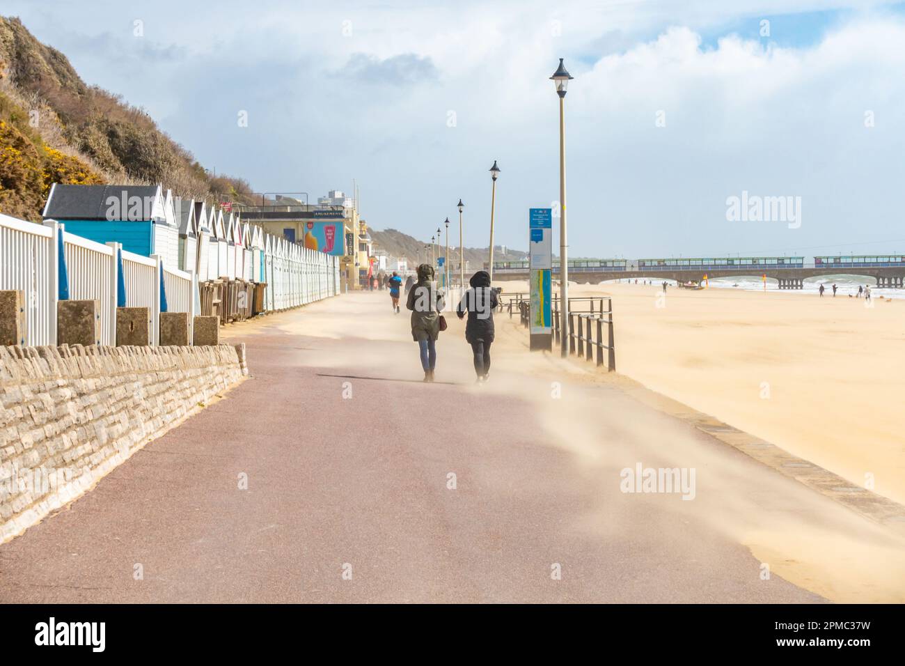 People walking along a path alongside Bournemouth Beach in Dorset, UK ...