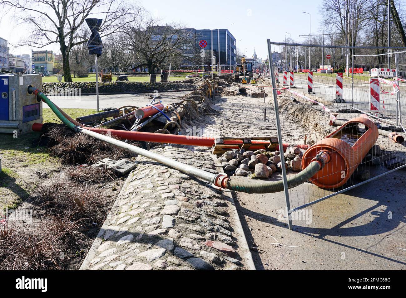 Street repair works site dewatering system with water pump, pipes and ...