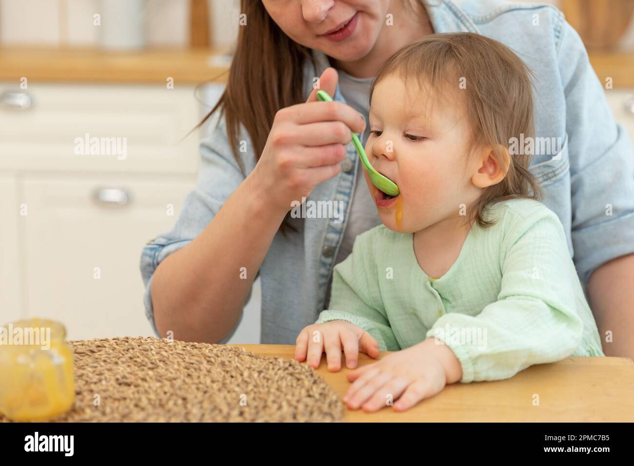 Happy family at home. Mother feeding her baby girl from spoon in ...