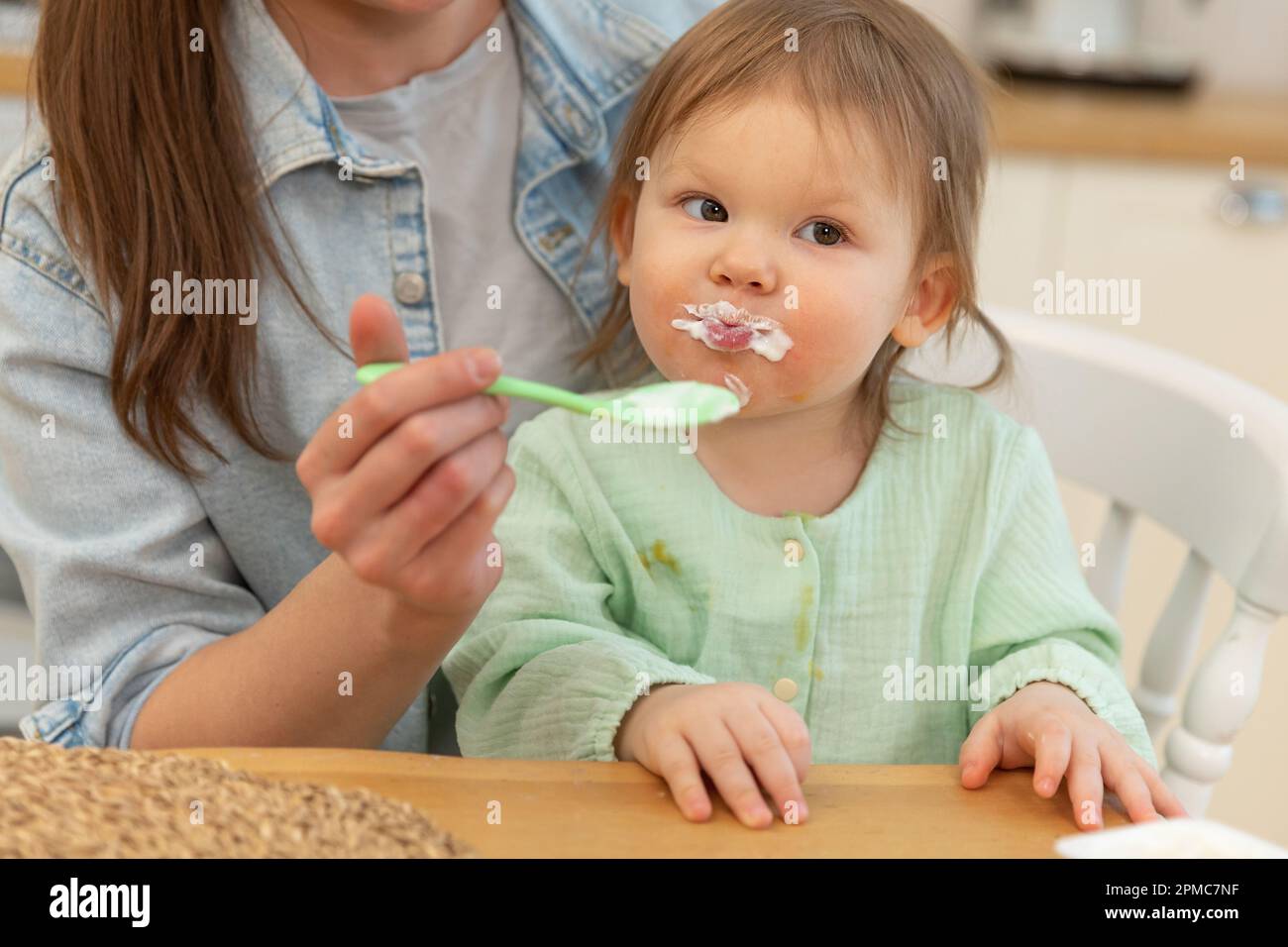 Happy family at home. Mother feeding her baby girl from spoon in ...