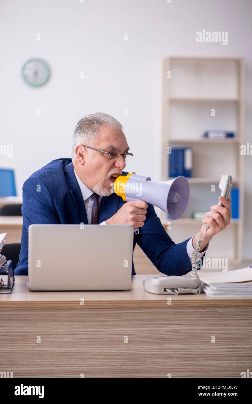 Old employee holding megaphone in the office Stock Photo - Alamy