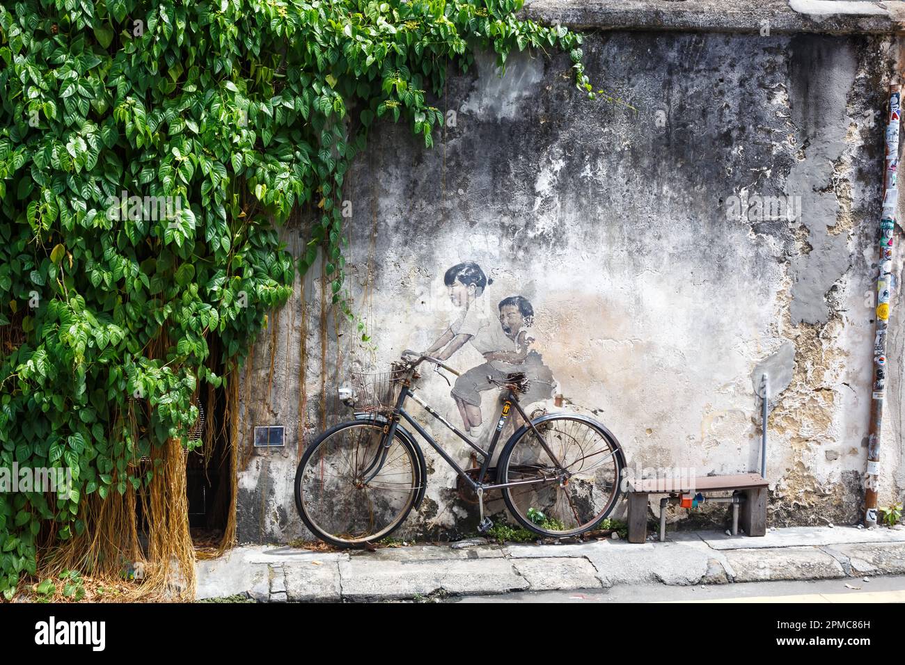 Street Art mural boy and girl on bicycle bike on a wall in George Town on Penang island in ...