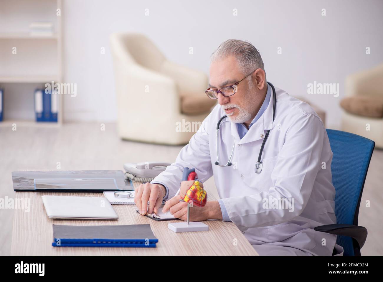 Old doctor cardiologist working in the clinic Stock Photo - Alamy