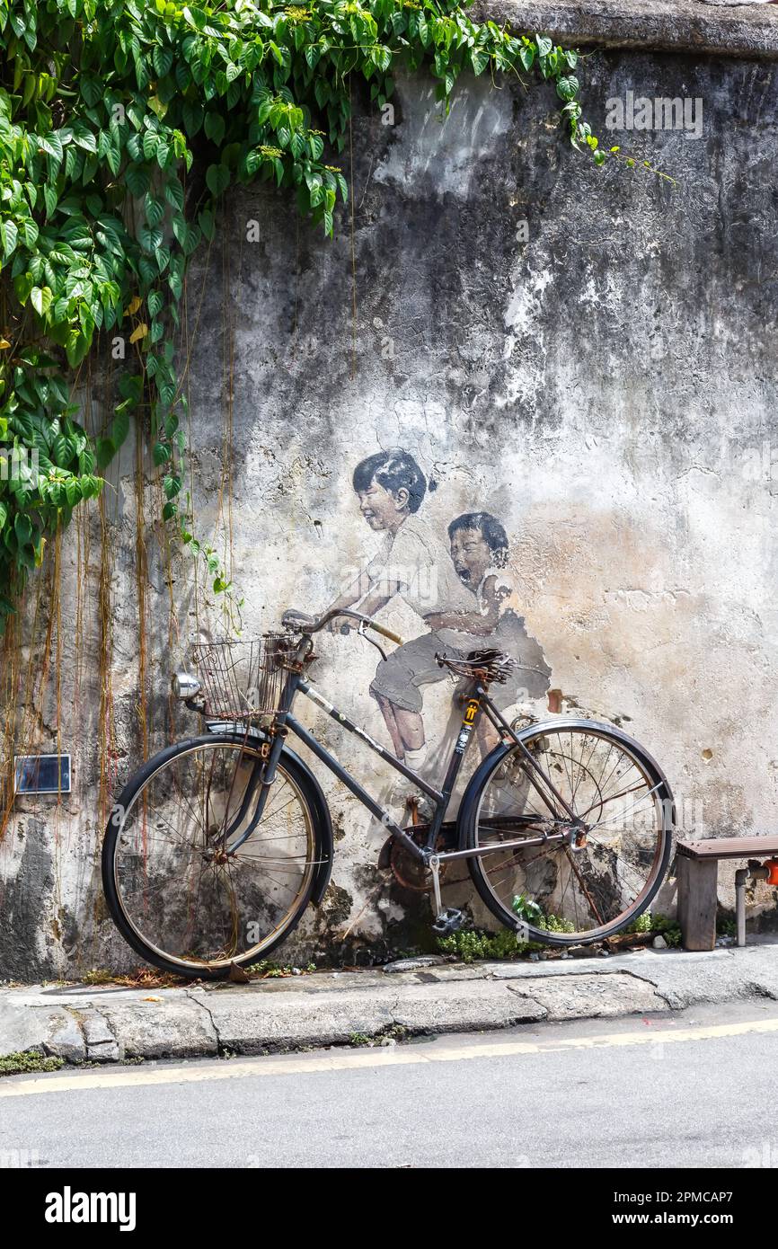Street Art mural boy and girl on bicycle bike on a wall portrait format in George Town on Penang ...