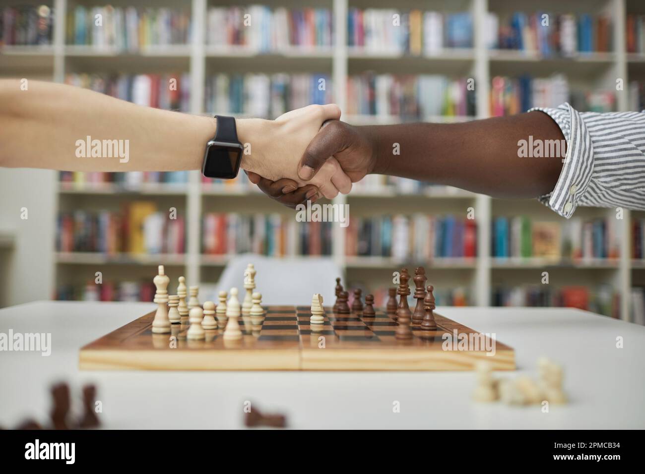 Side view close up of two chess players shaking hands over chess board ...