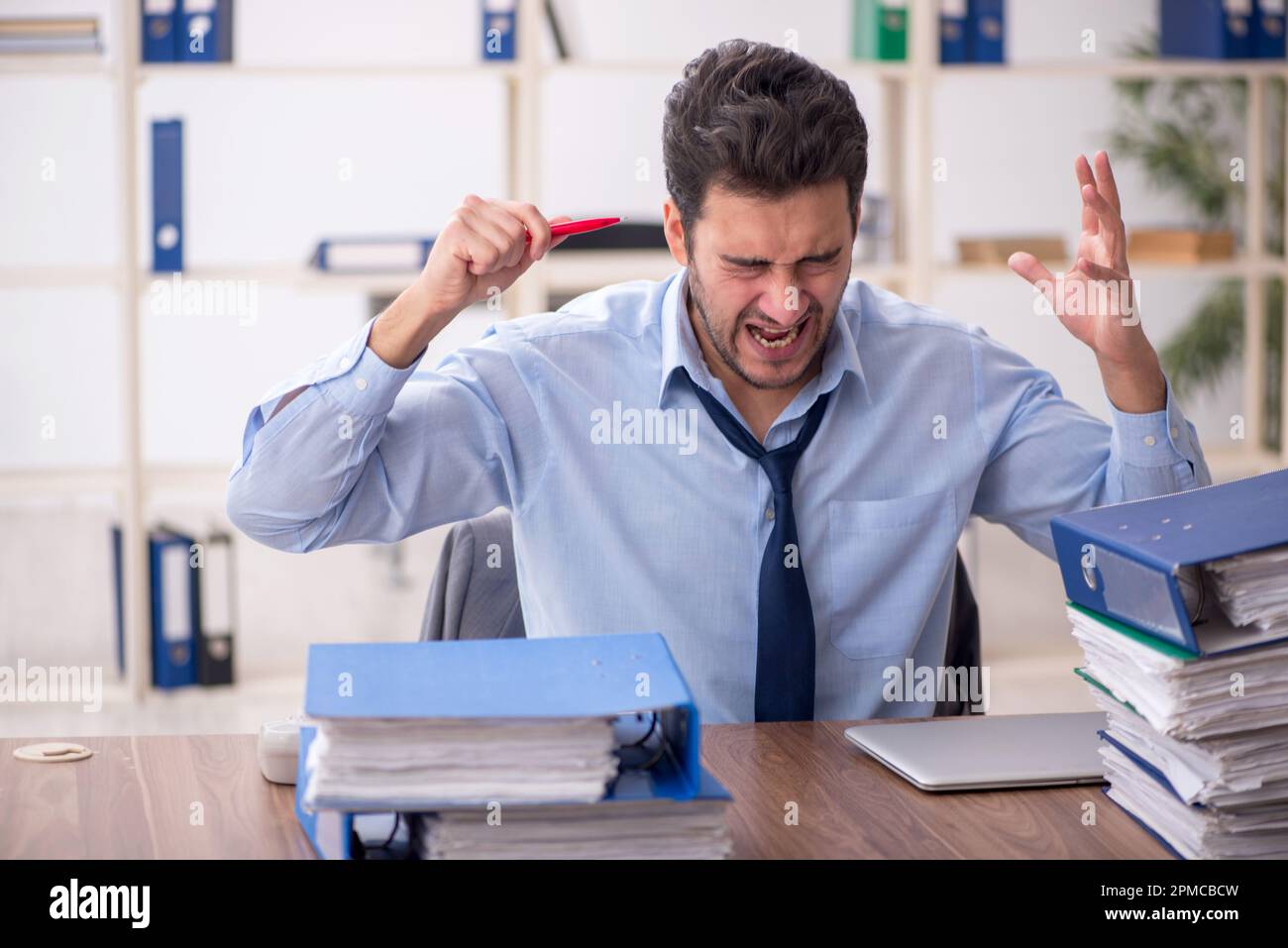 Young employee and too much work at workplace Stock Photo - Alamy