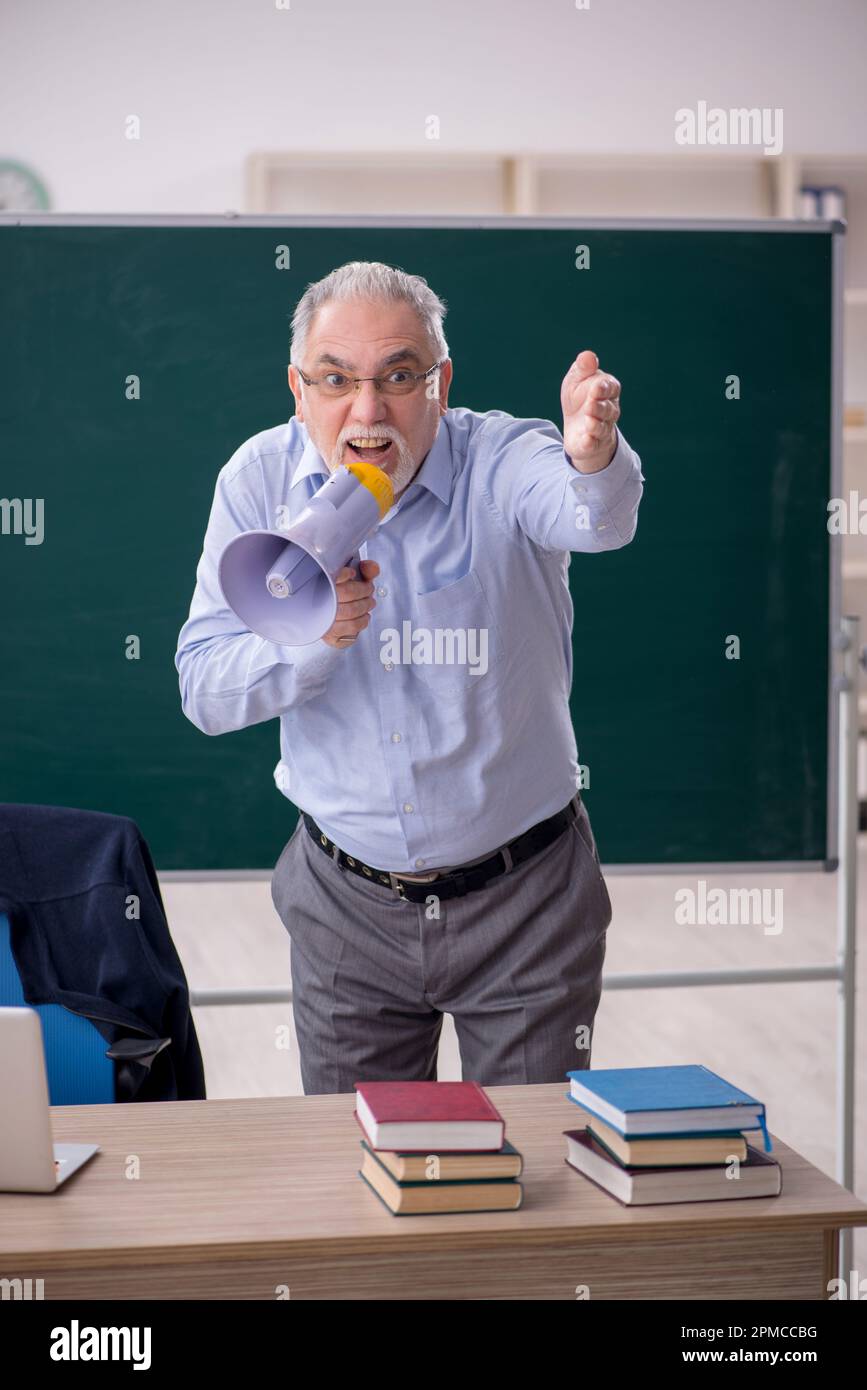 Old teacher holding megaphone in the classroom Stock Photo - Alamy