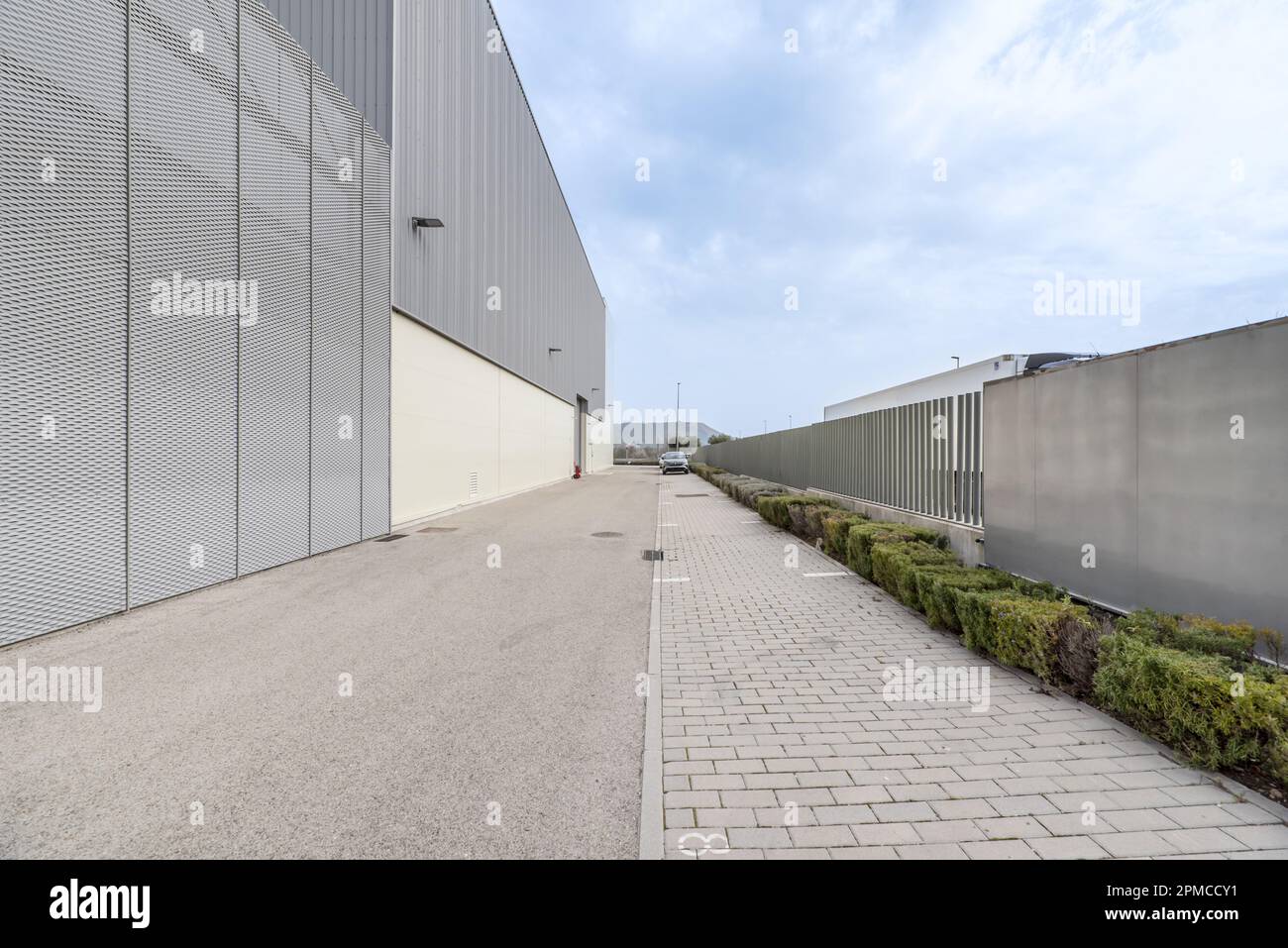 Facade of an industrial warehouse with gardens and parking area for ...
