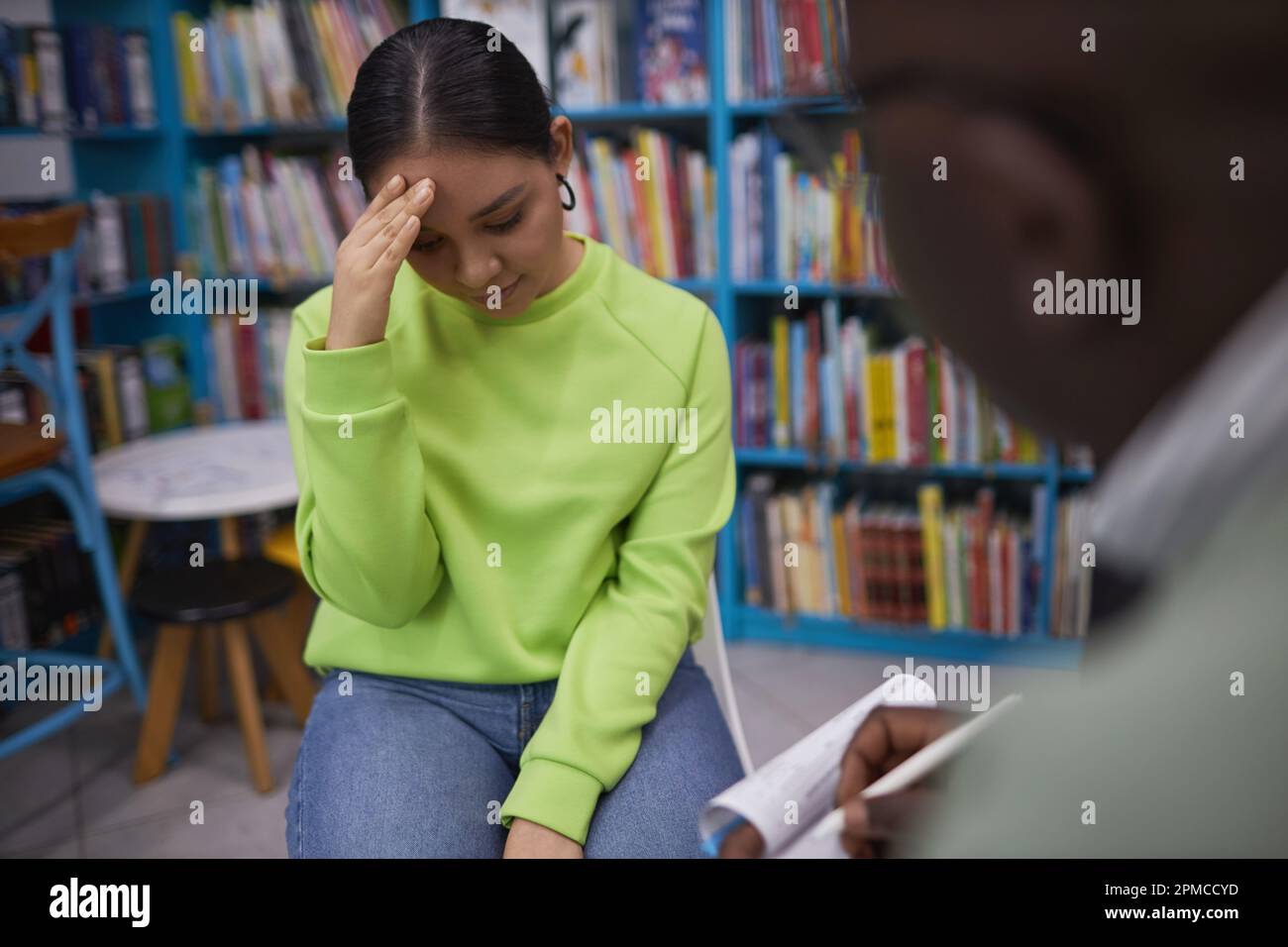 Portrait of stressed young woman hiding face in therapy session with ...