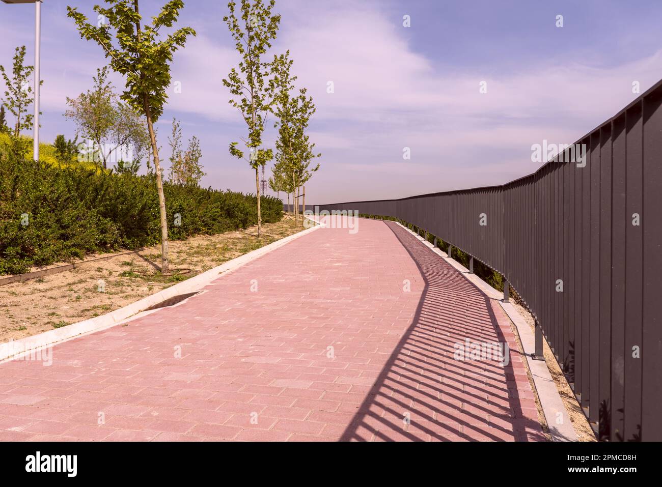Walkways with metal railing in an urban park with young trees Stock ...