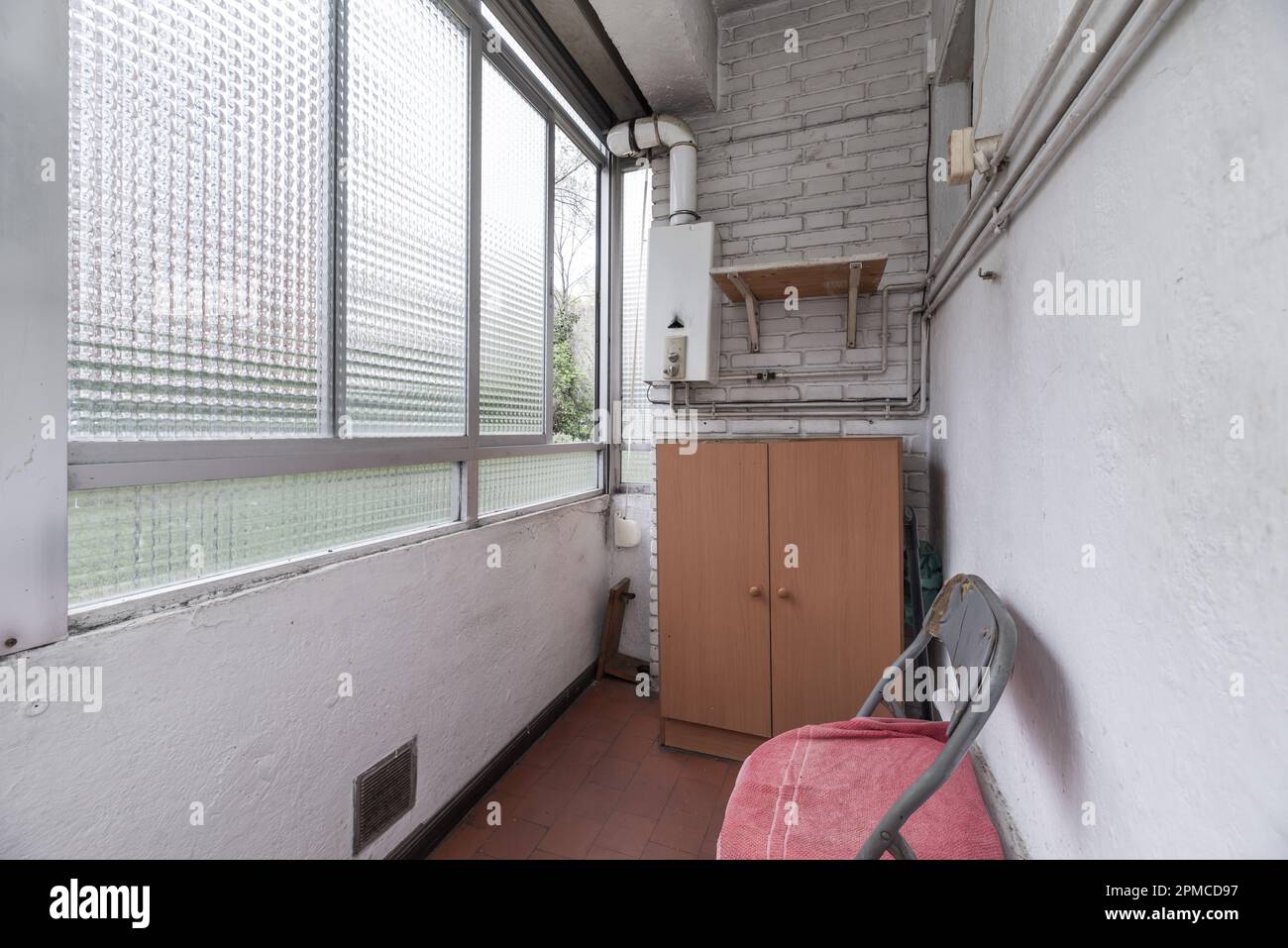 A small closed terrace with a glass window and a gas heater on a white ...