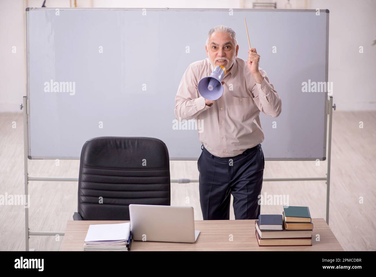 Old teacher holding megaphone in the classroom Stock Photo - Alamy