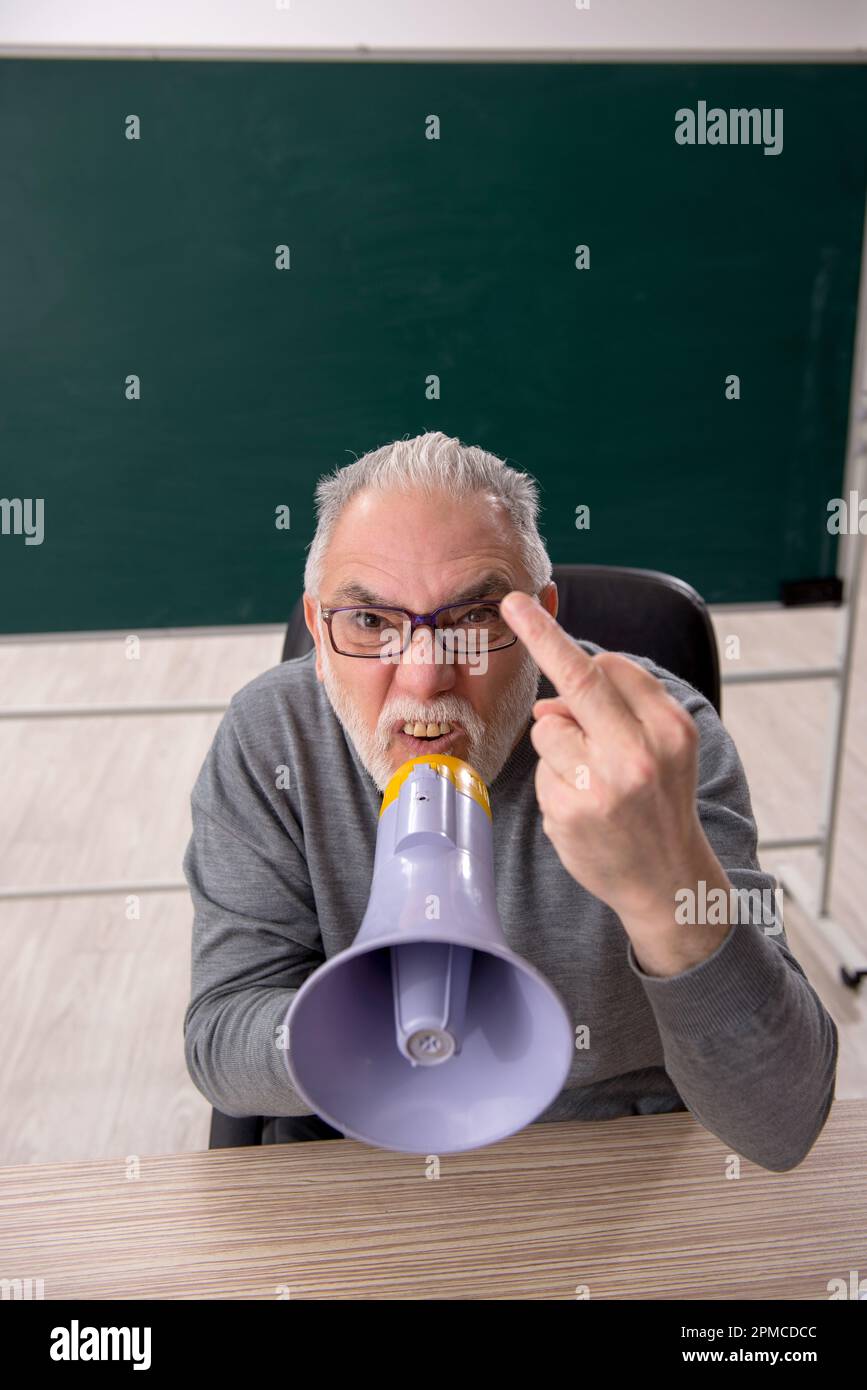 Old teacher holding megaphone in the classroom Stock Photo - Alamy