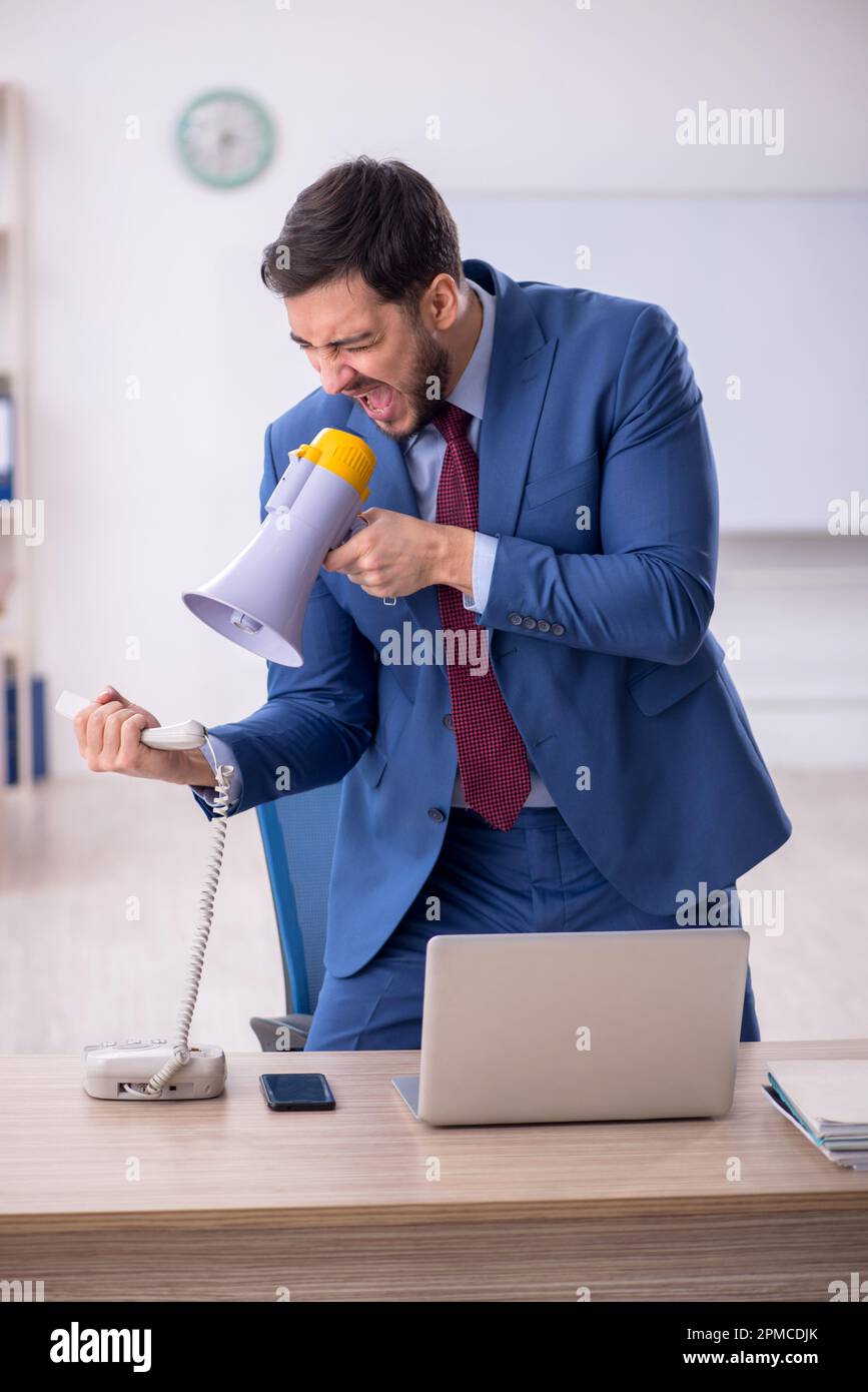 Young employee holding megaphone in the office Stock Photo - Alamy