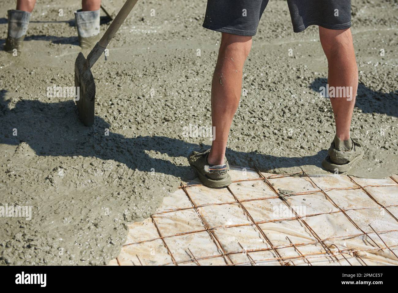 Soiled construction worker stands with his feet in concrete on a ...