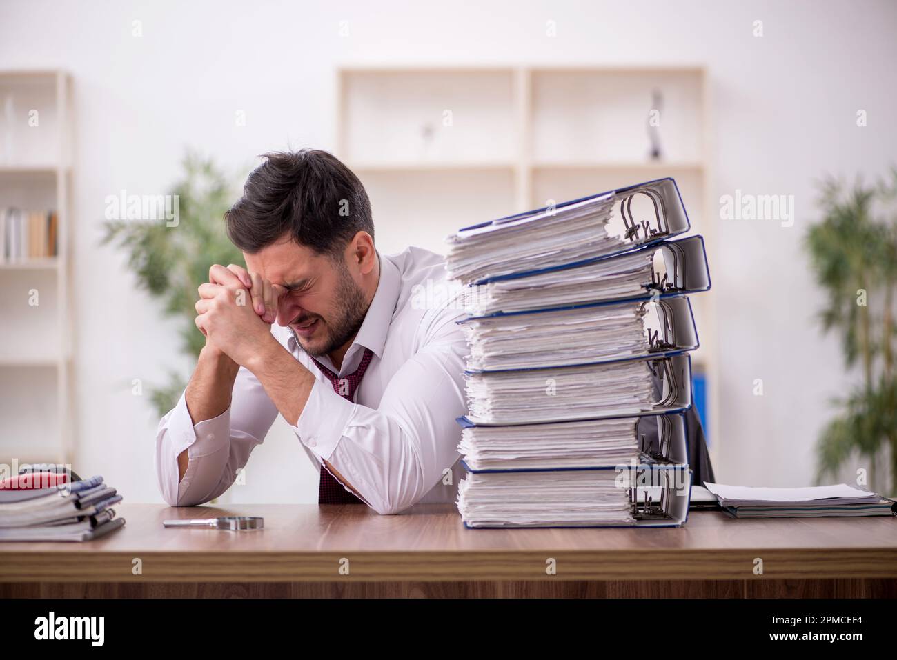 Young employee and too much work in the office Stock Photo - Alamy
