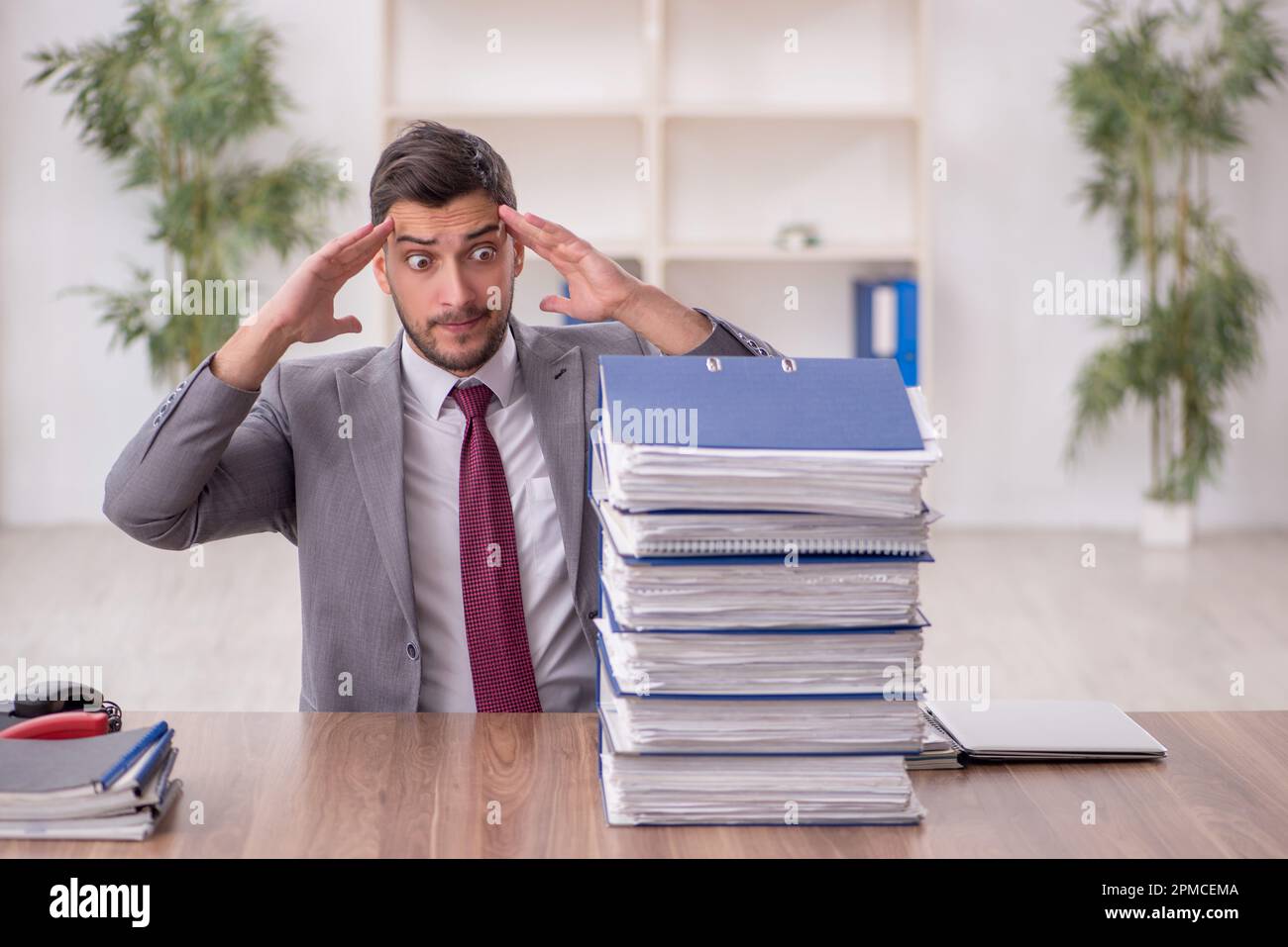 Young employee and too much work in the office Stock Photo - Alamy