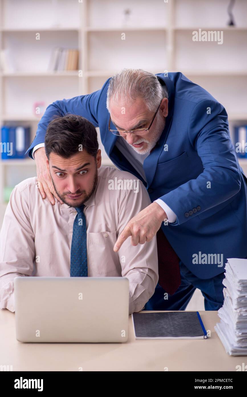 Old boss and young employee in bullying concept Stock Photo - Alamy