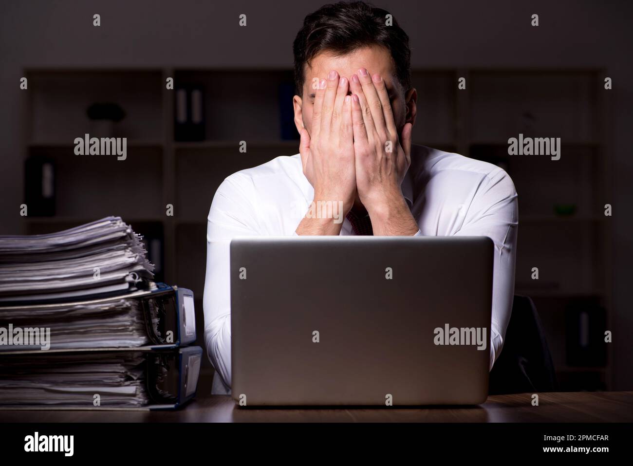 Young employee working late at workplace Stock Photo - Alamy