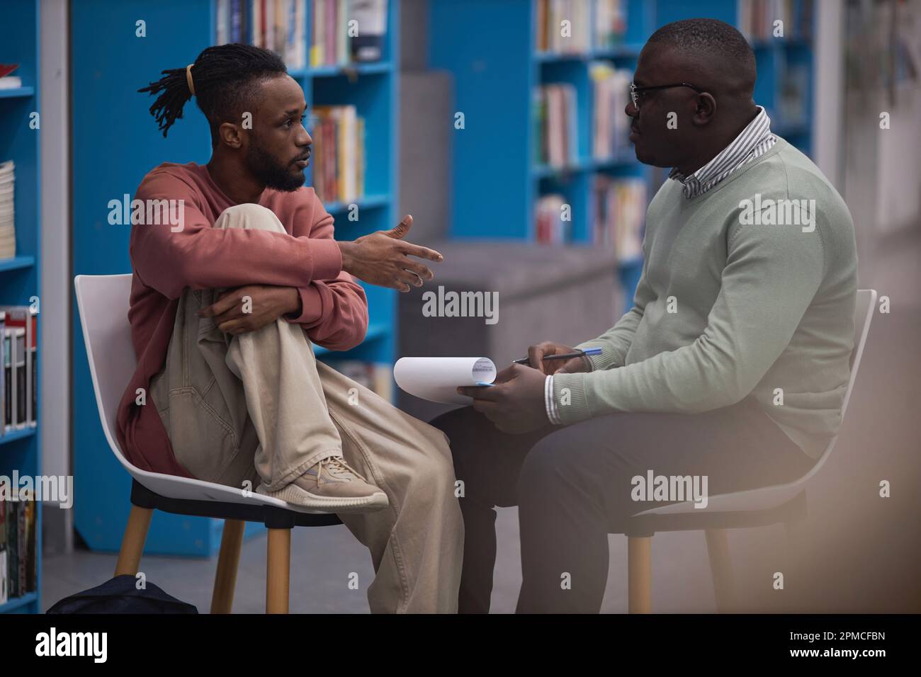 Side view portrait of black student talking to mental health therapist ...