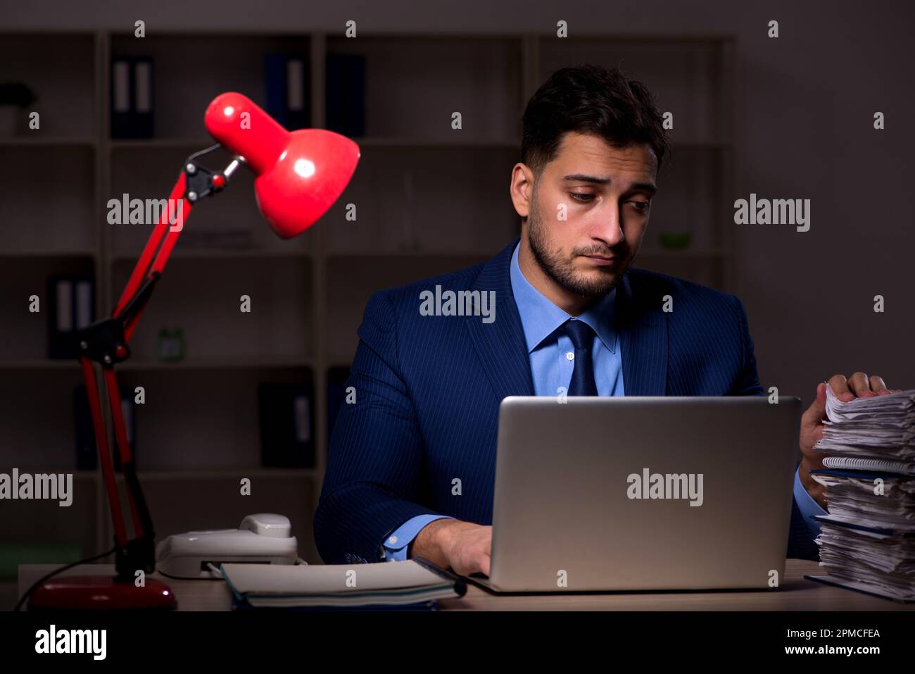 Young employee working late at workplace Stock Photo - Alamy