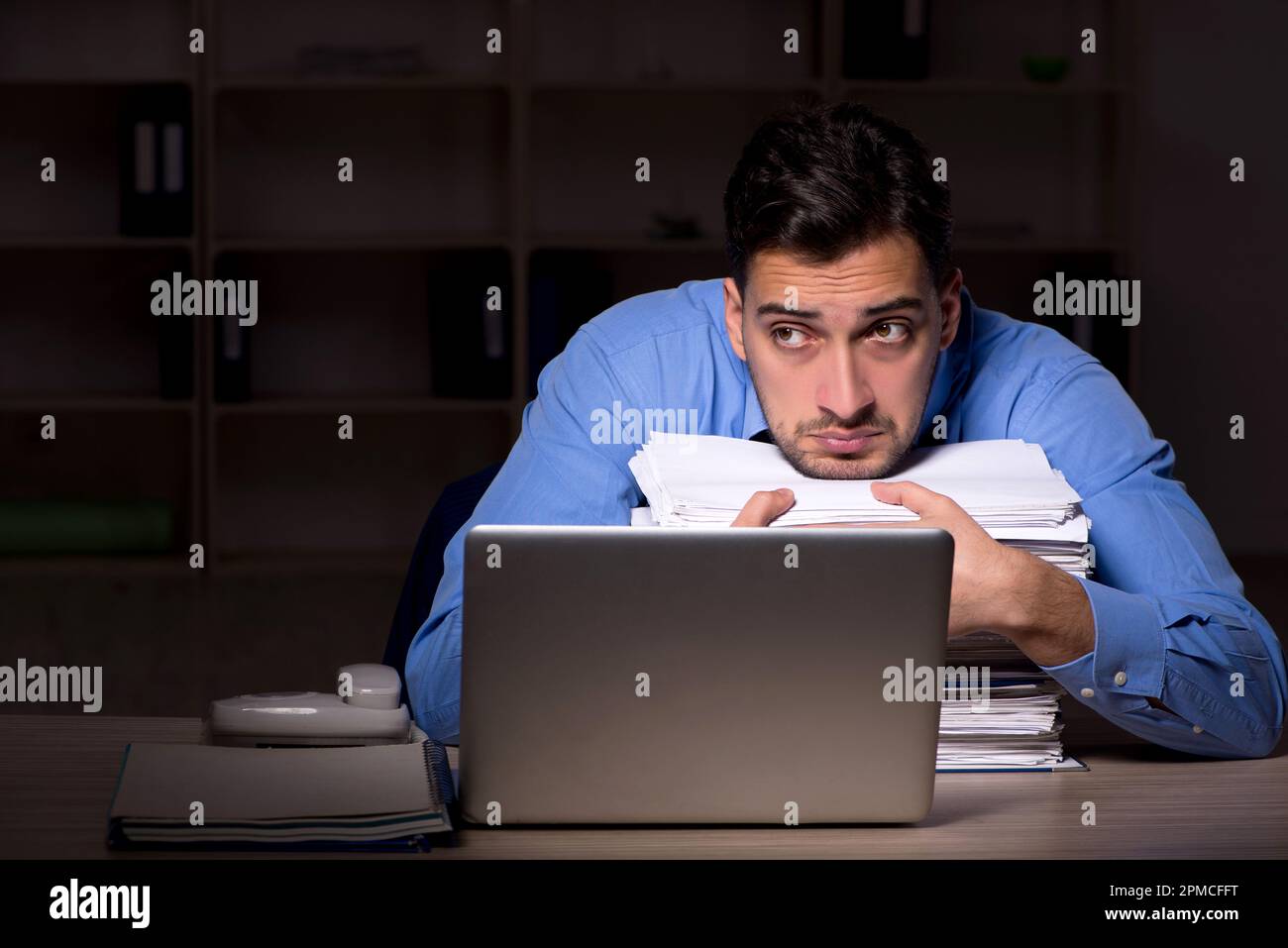 Young employee working late at workplace Stock Photo - Alamy