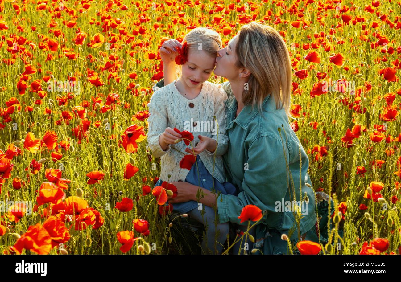 Mother with daughter outdoor in poppy field. Mom hugs lovely child on ...