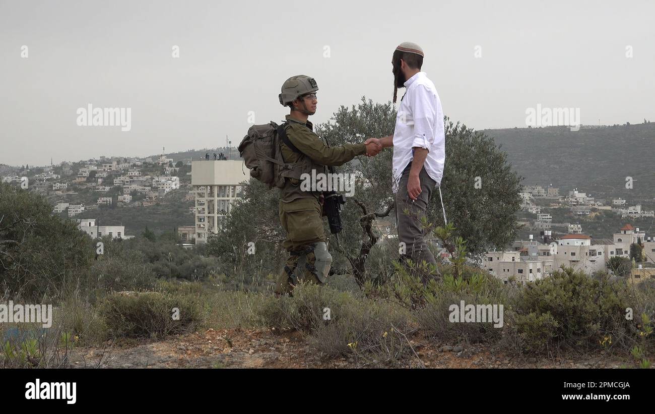 A Jewish settler greets an Israeli soldier standing guard in the West ...