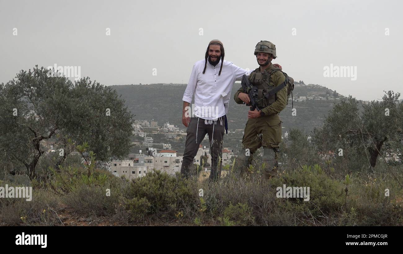 A Jewish settler hugs an Israeli soldier standing guard in the West ...