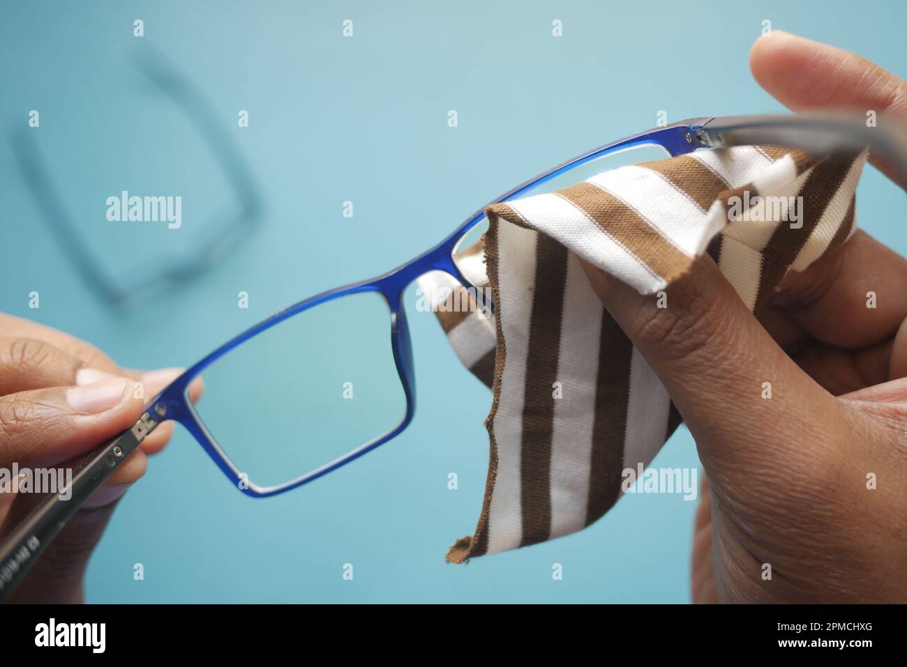 cleaning eyeglass with tissue close up Stock Photo - Alamy