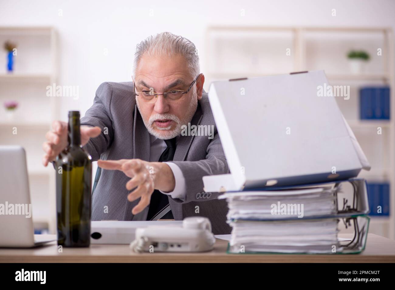 Old employee drinking alcohol at workplace Stock Photo - Alamy