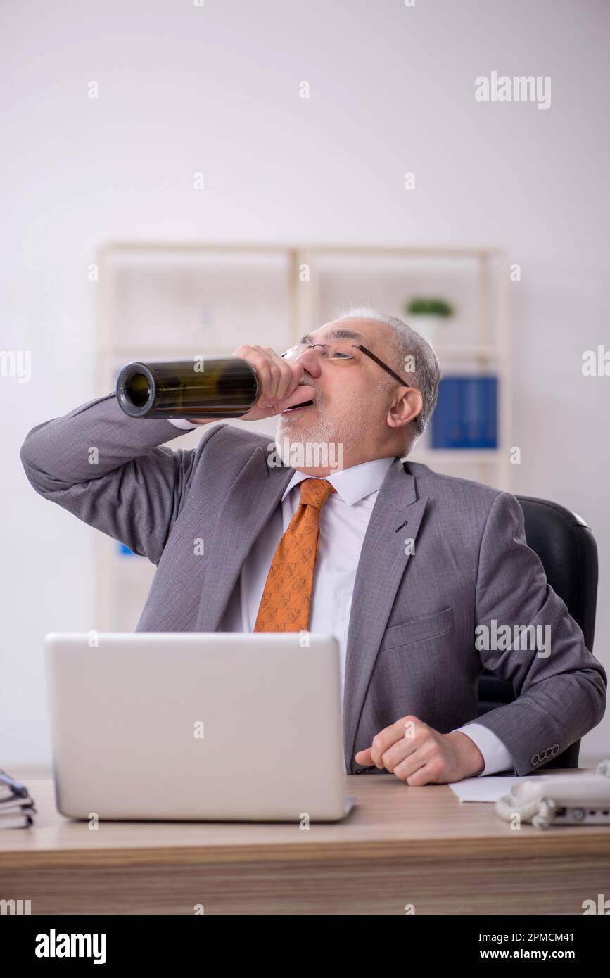 Old employee drinking alcohol at workplace Stock Photo - Alamy