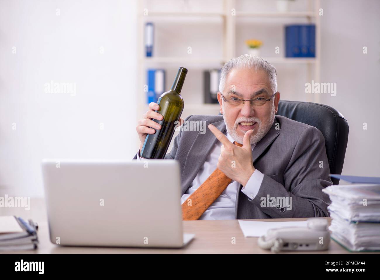Old employee drinking alcohol at workplace Stock Photo - Alamy