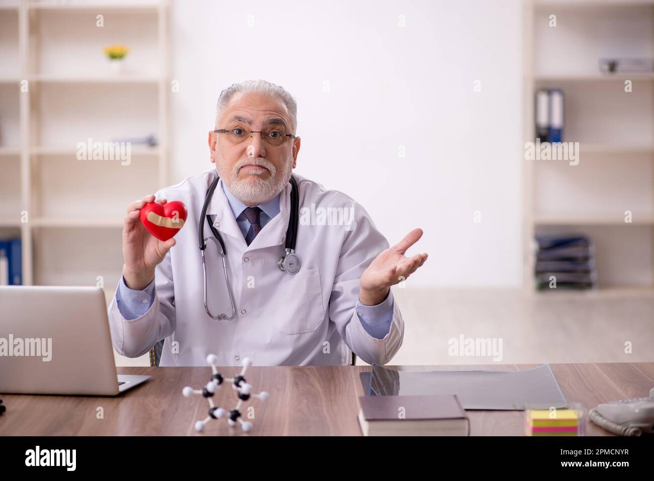 Old cardiologist holding heart model Stock Photo - Alamy