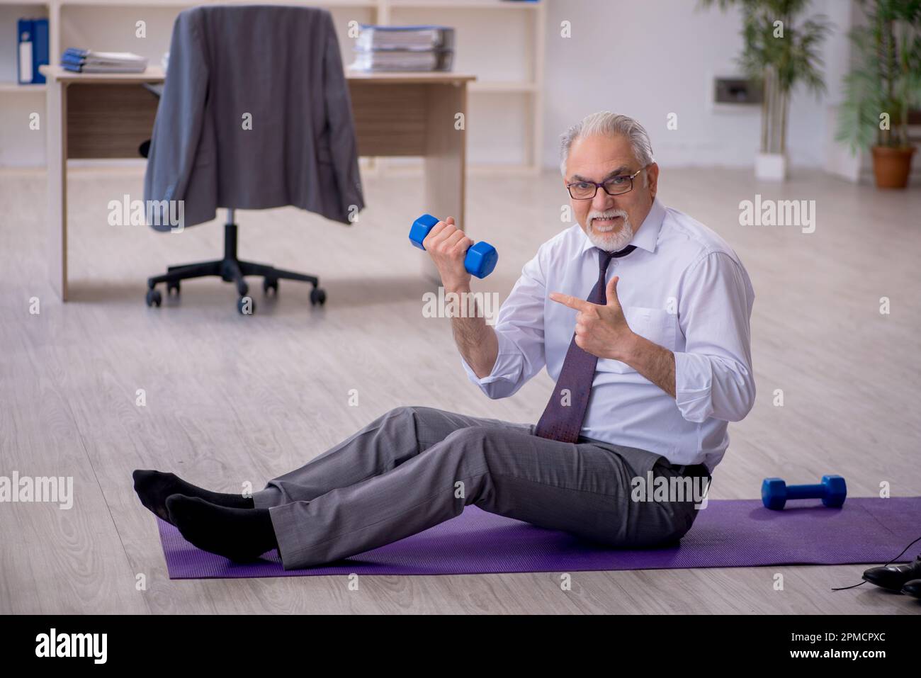 Old employee doing sport exercises during break Stock Photo - Alamy
