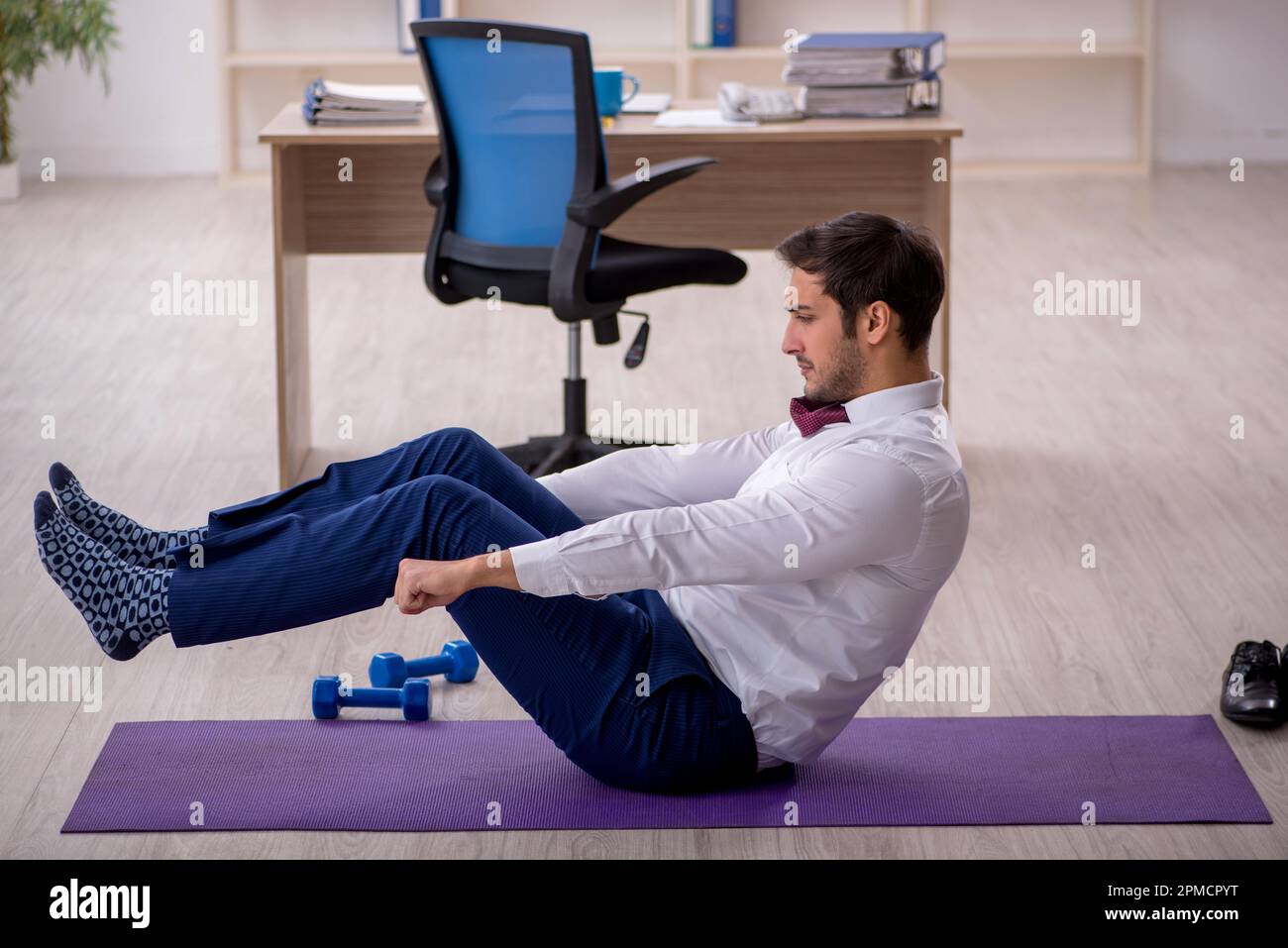 Young employee doing sport exercises during break Stock Photo - Alamy