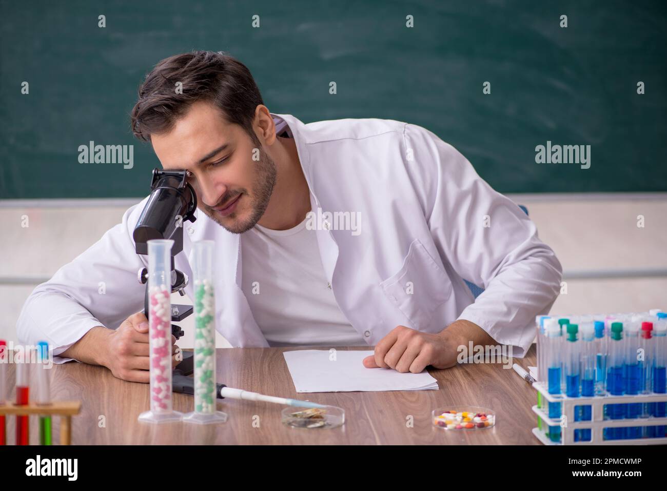 Young chemist in front of green board Stock Photo - Alamy