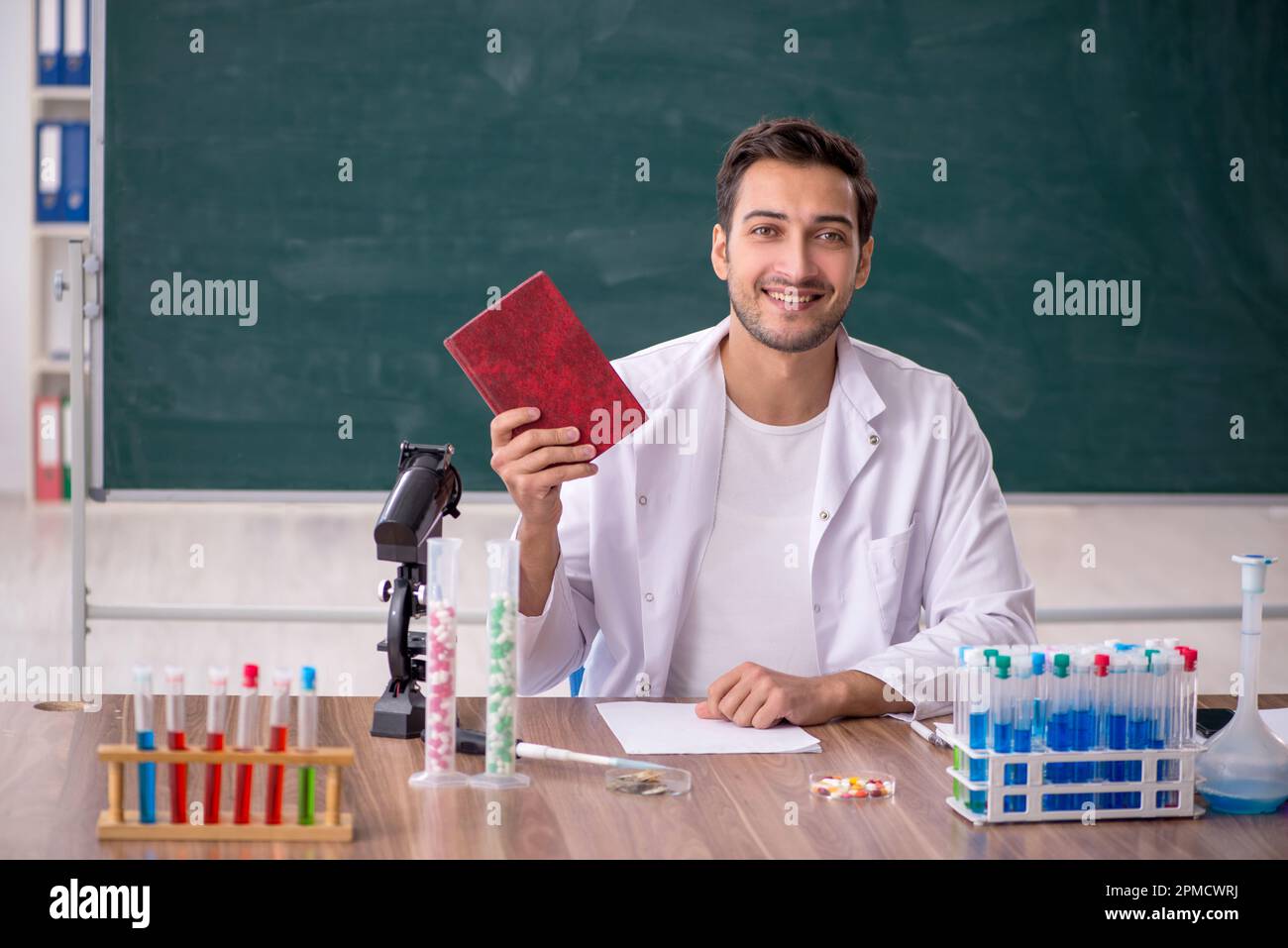 Young chemist in front of green board Stock Photo - Alamy