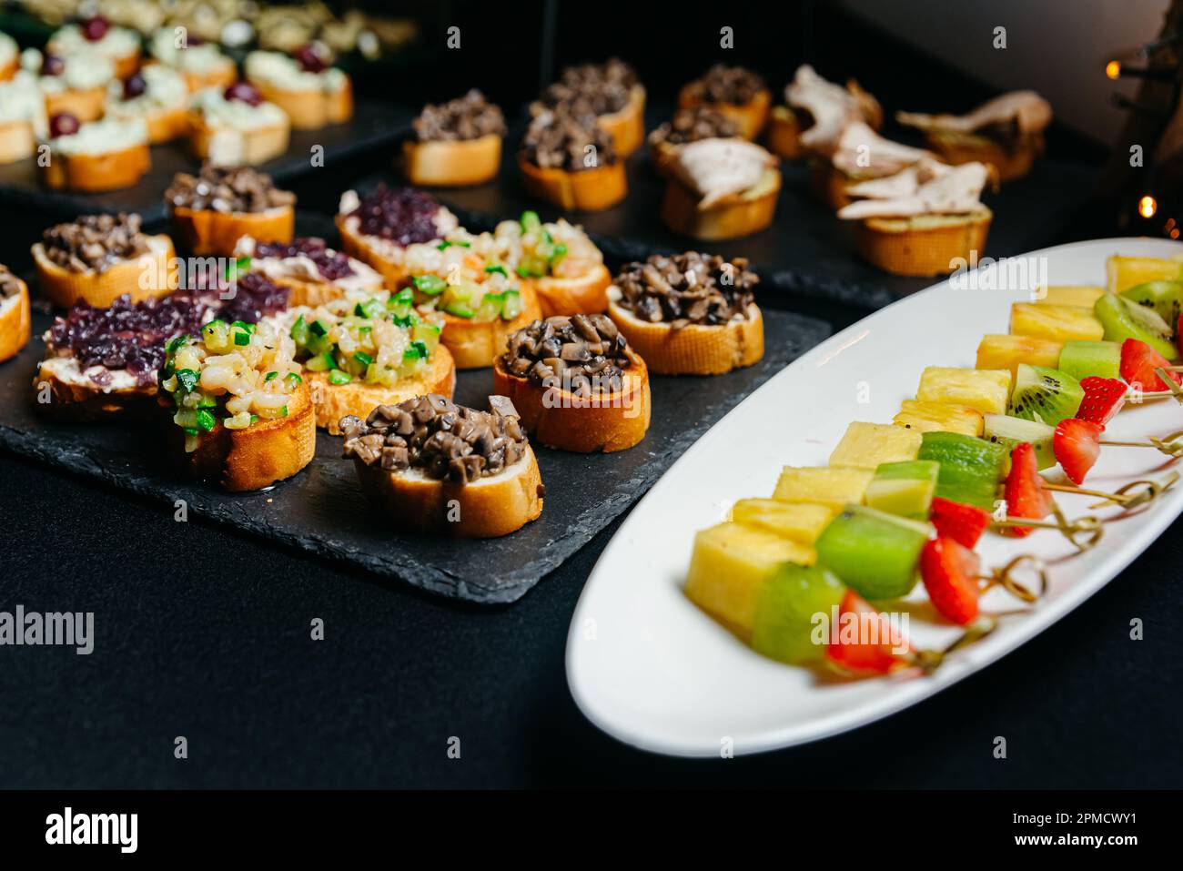 catering food on a black background. fruit canapes and veggie ...