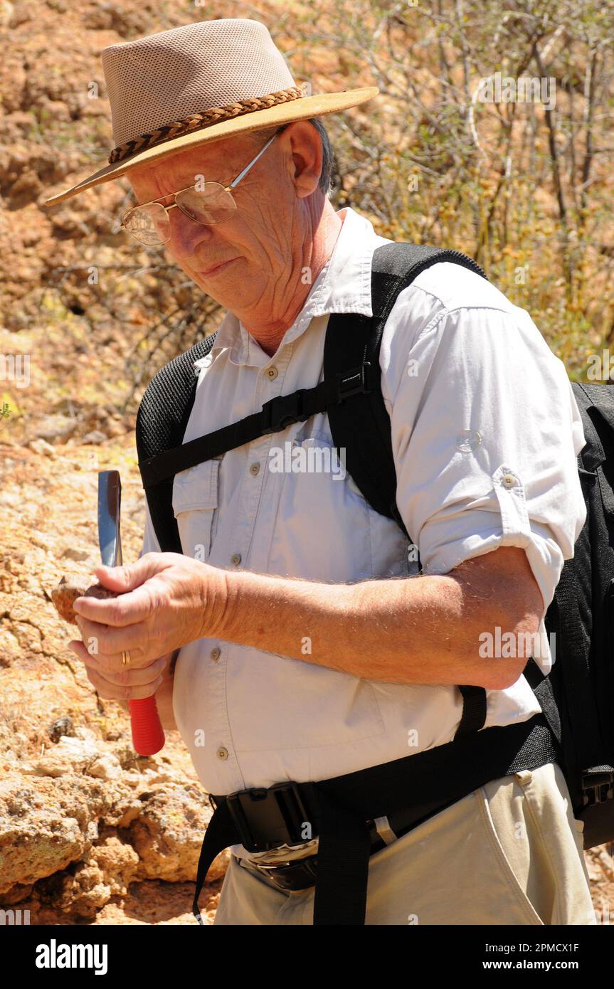 Senior geologist tap a rock formation with a hammer Stock Photo - Alamy