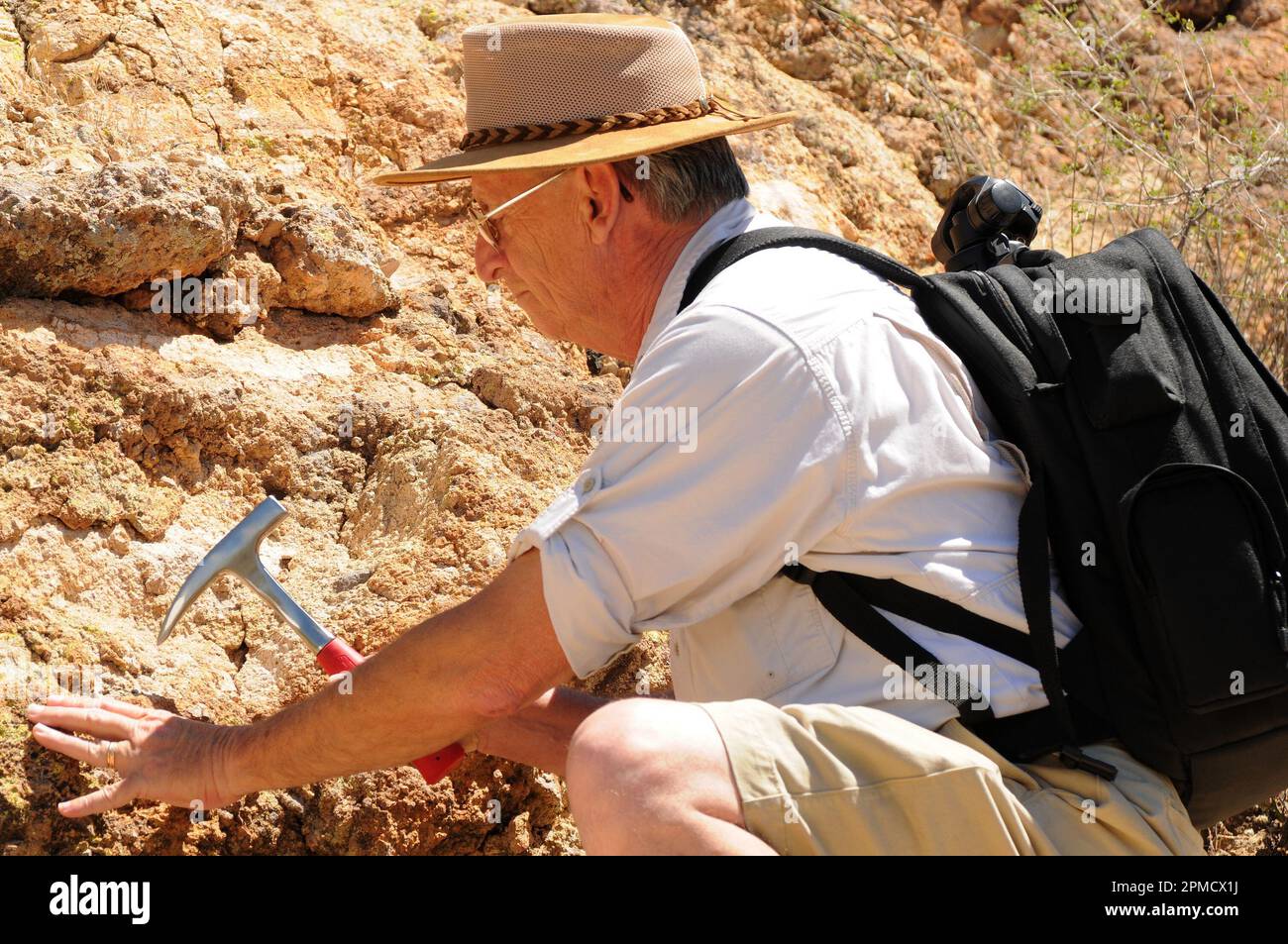 Senior geologist tap a rock formation with a hammer Stock Photo - Alamy