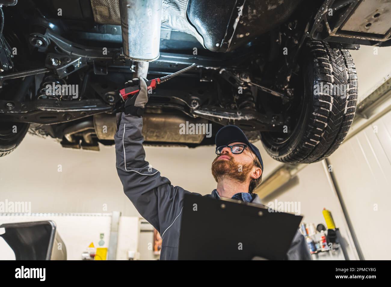 Mechanic repairing a car, Mechanic inspects car suspension system and ...