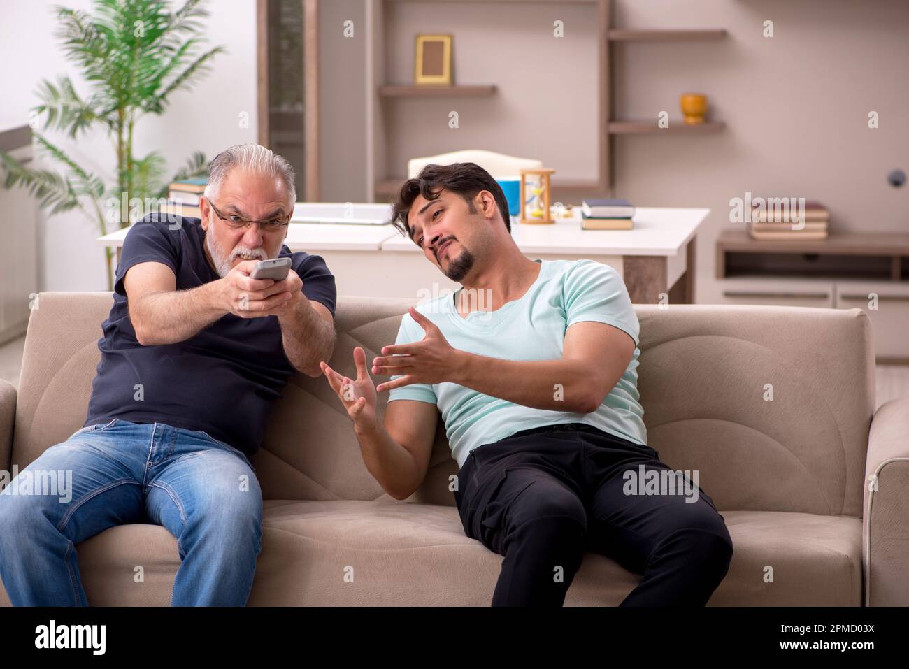 Old father and young son watching tv during pandemic Stock Photo - Alamy