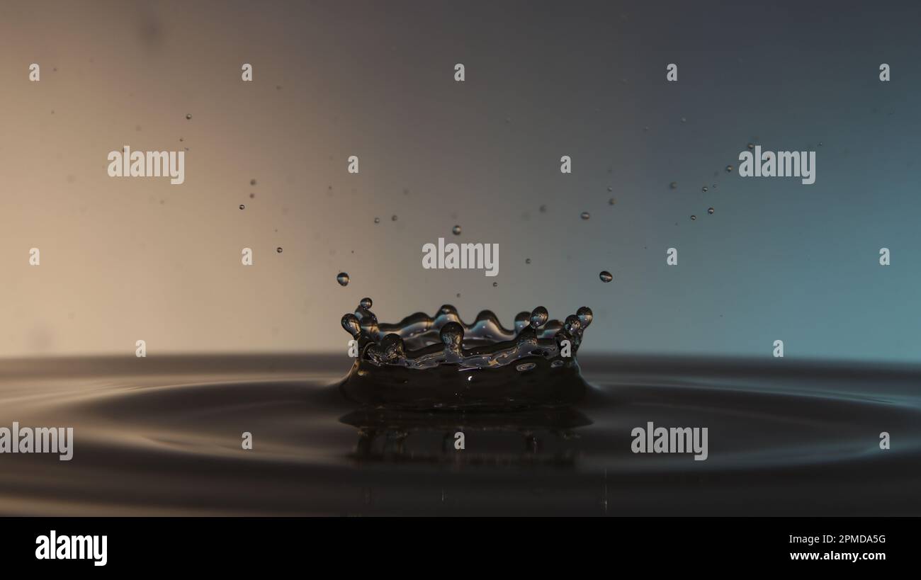 Water crown splash with droplets frozen in mid-air on a warm–cool ...
